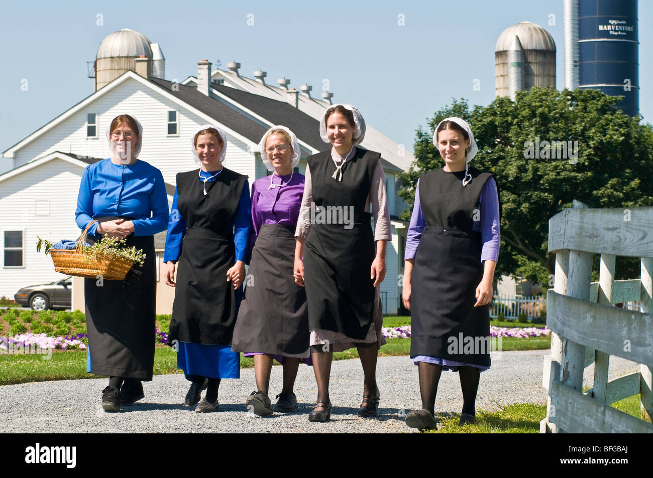 Young amish women friends walking down country lane road in Lancaster ...
