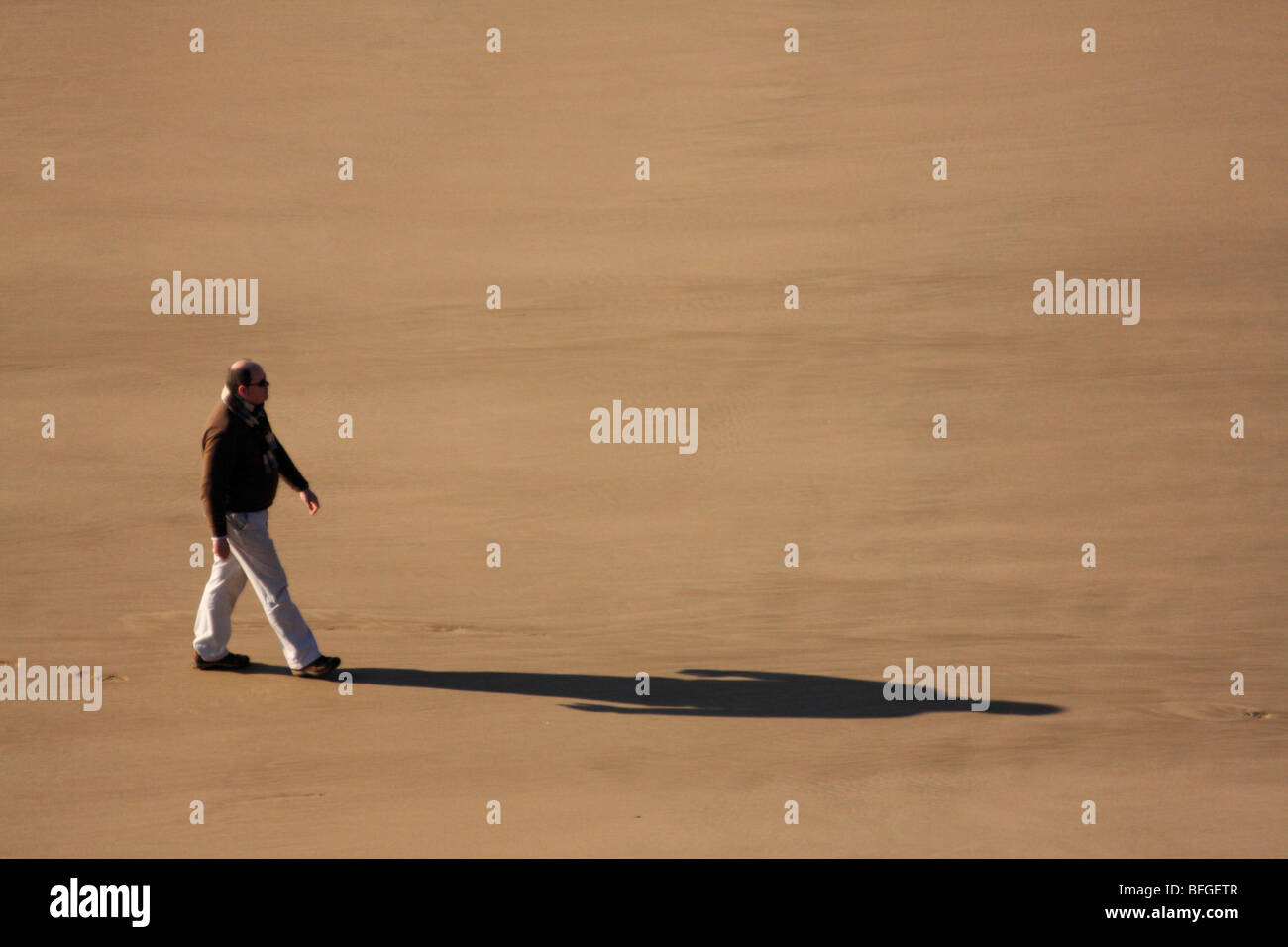Single Man Walking Along a Sandy Beach, viewed from above, and casting ...