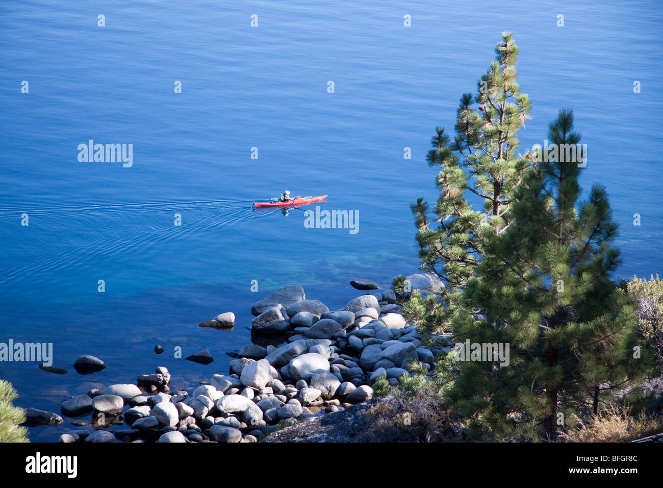 Lone kayaker passing a bouldered shore, on the north shore of Lake ...