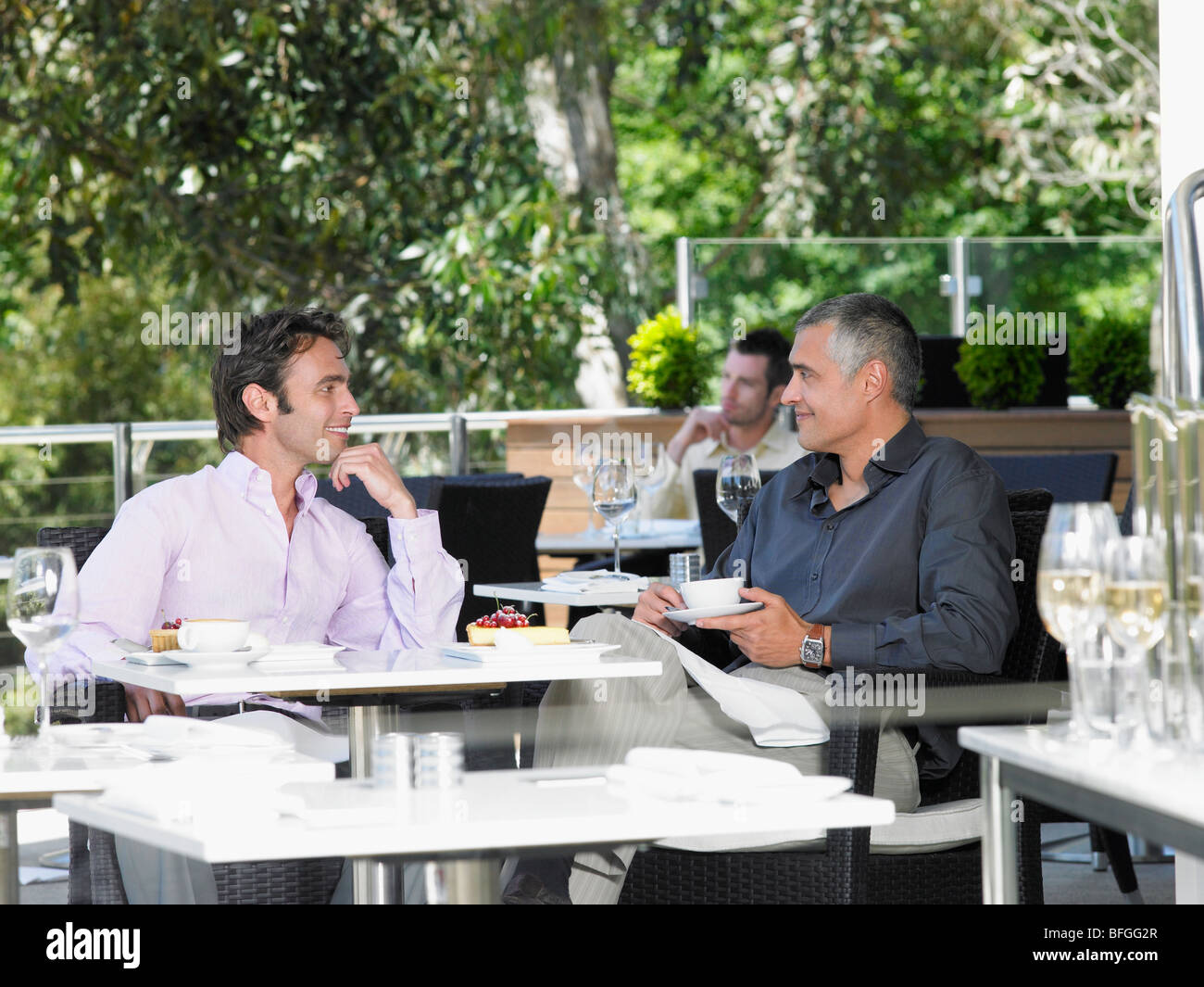 Two men talking at outdoor cafe Stock Photo - Alamy