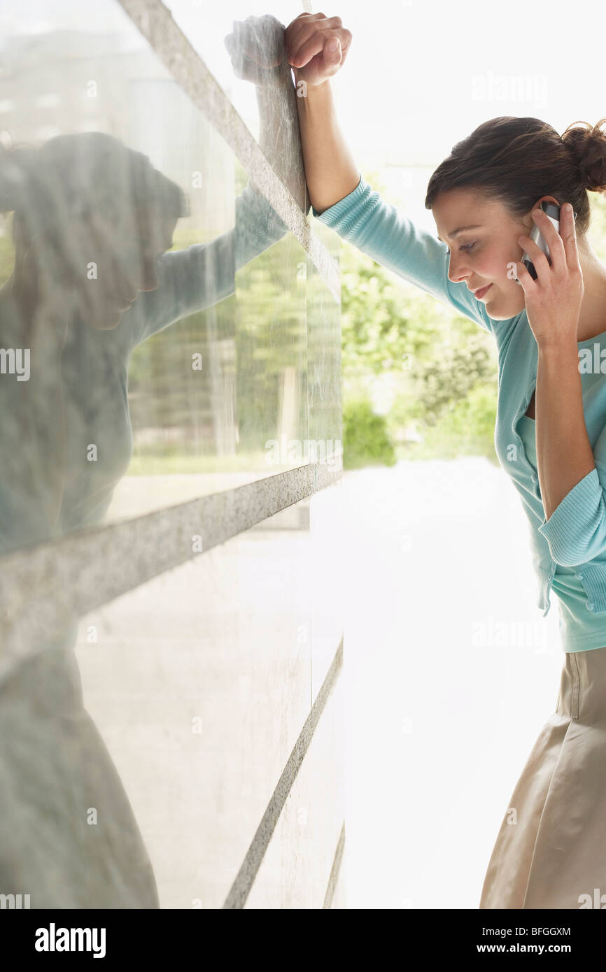 Young Woman using mobile phone, leaning, side view Stock Photo - Alamy