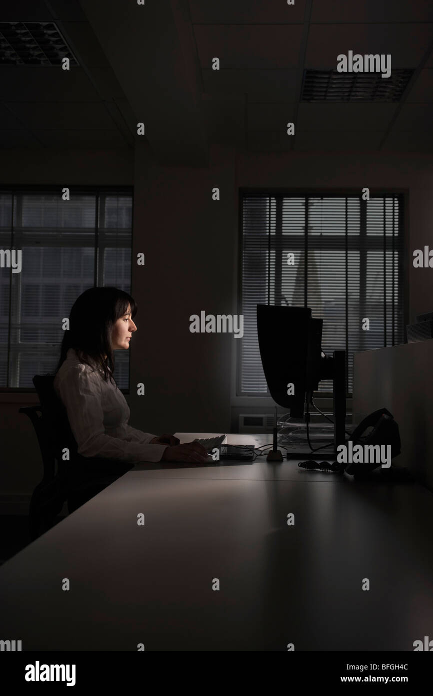 Female office worker using computer in darkened office, side view Stock ...