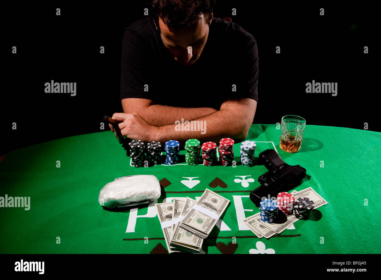A young depressed male gambler at the gambling table gun and drugs in ...
