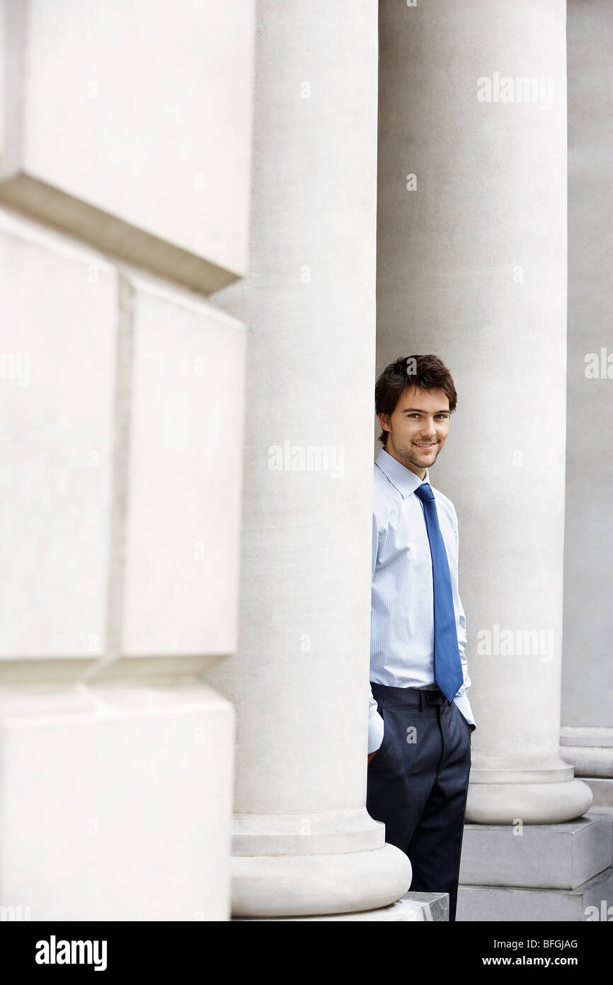 Businessman standing outside building by pillar, portrait Stock Photo ...