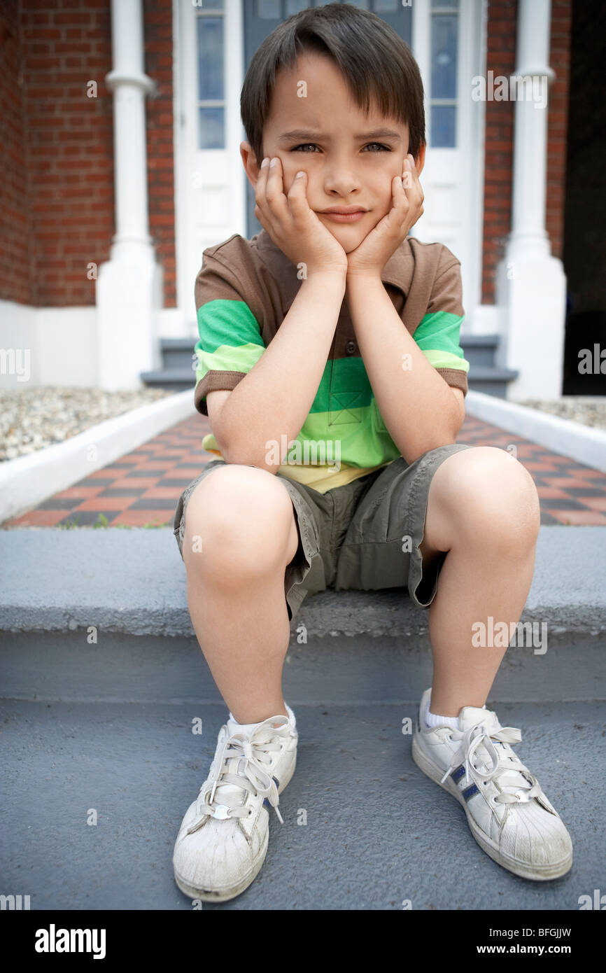 Sad little boy sitting on front steps of house Stock Photo - Alamy