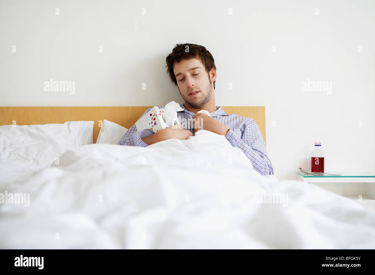 Man with cold in bed holding box of tissues Stock Photo - Alamy
