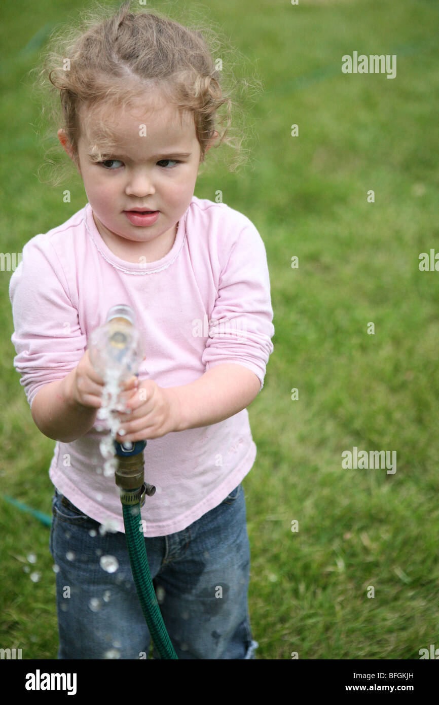 Little girl holding a garden hose Stock Photo - Alamy