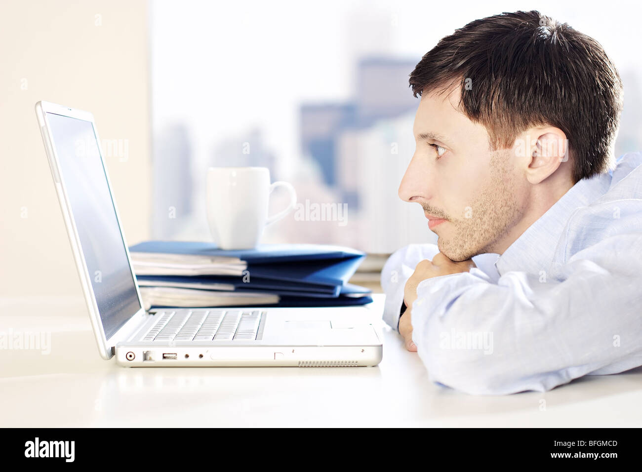 Man working at computer with window in background Stock Photo - Alamy