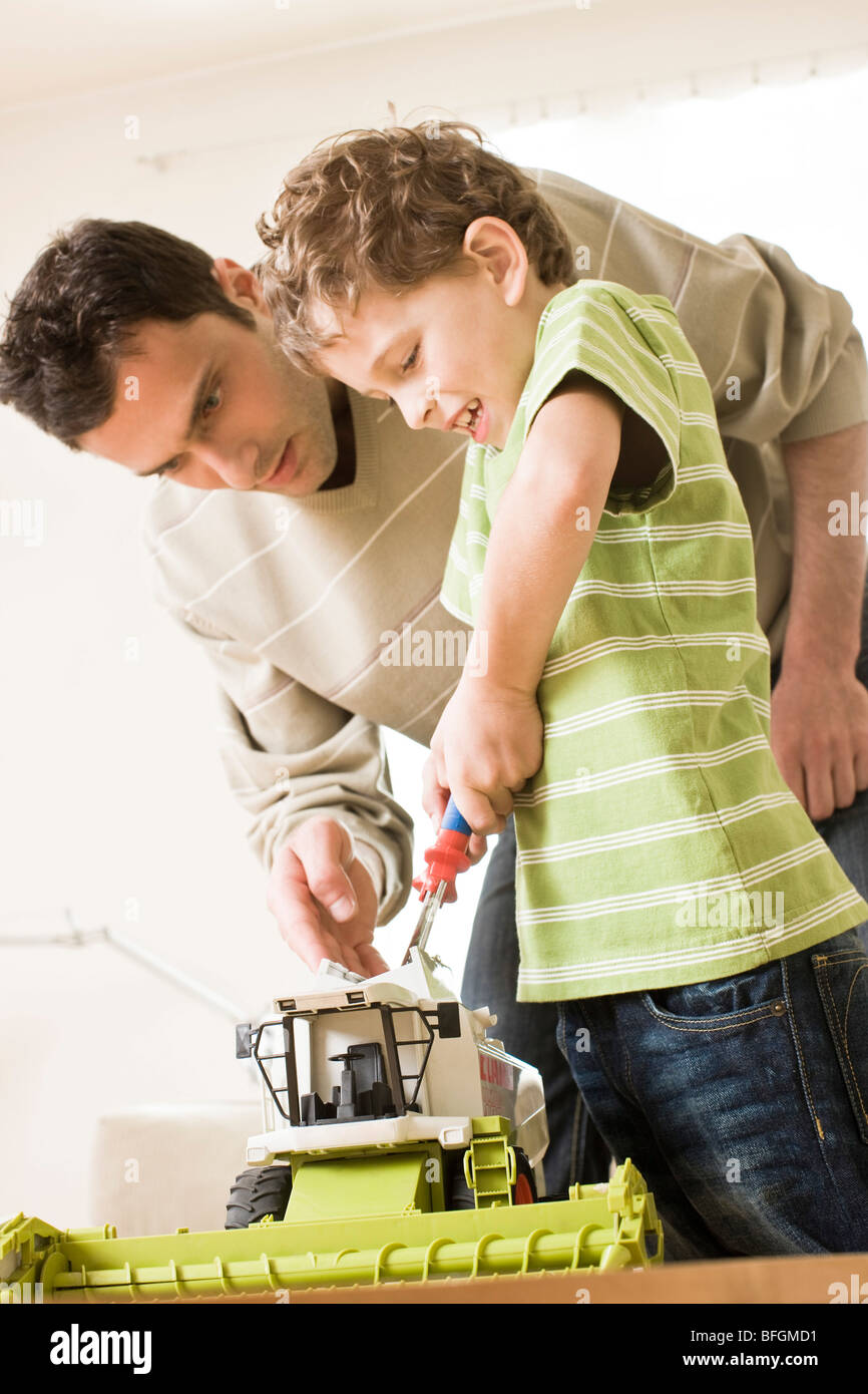 father fixing toy with son Stock Photo - Alamy