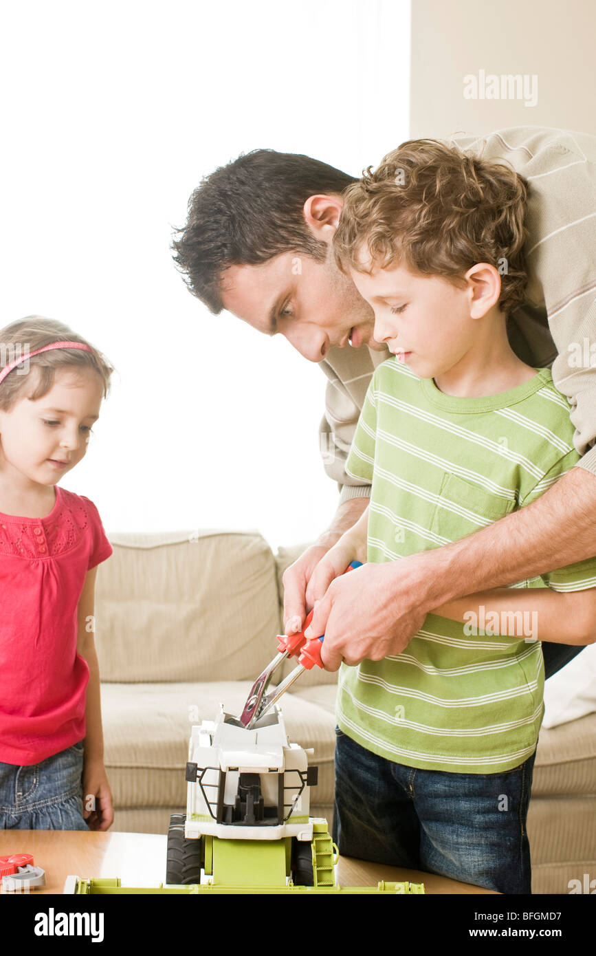 father fixing toy with son Stock Photo - Alamy
