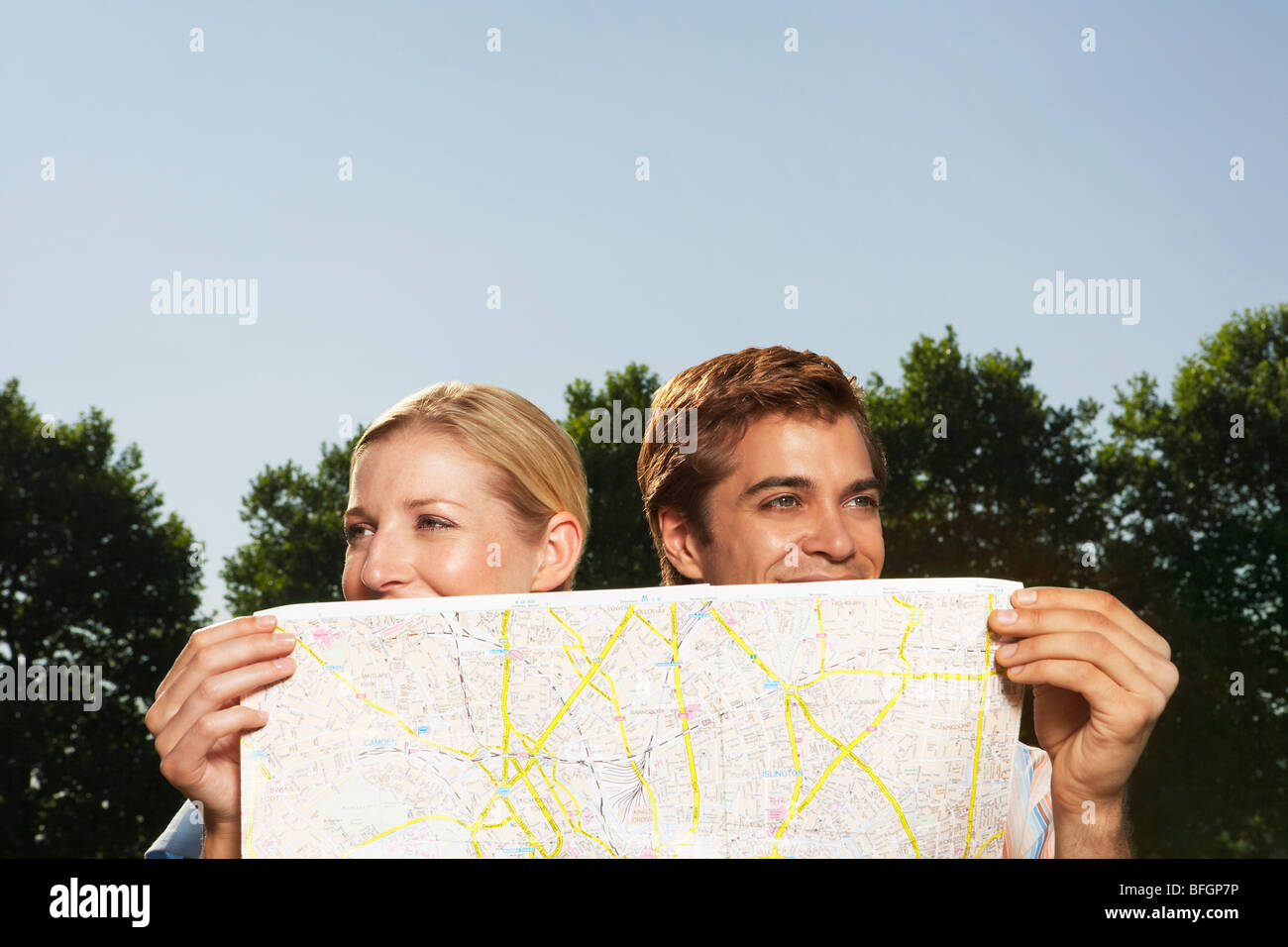 Lost smiling young couple in park holding map Stock Photo - Alamy