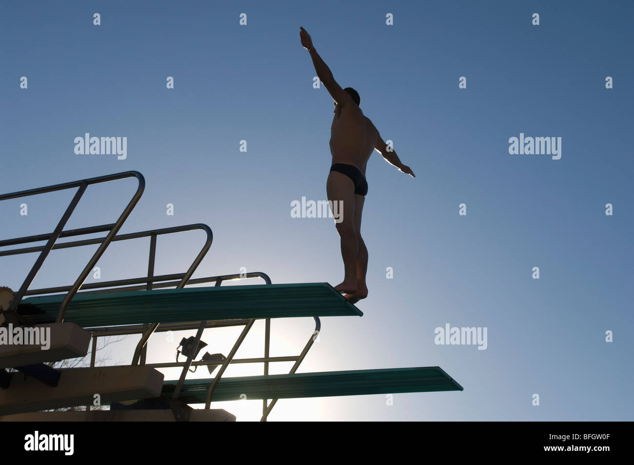 Swimmer standing on diving board at sunset Stock Photo - Alamy