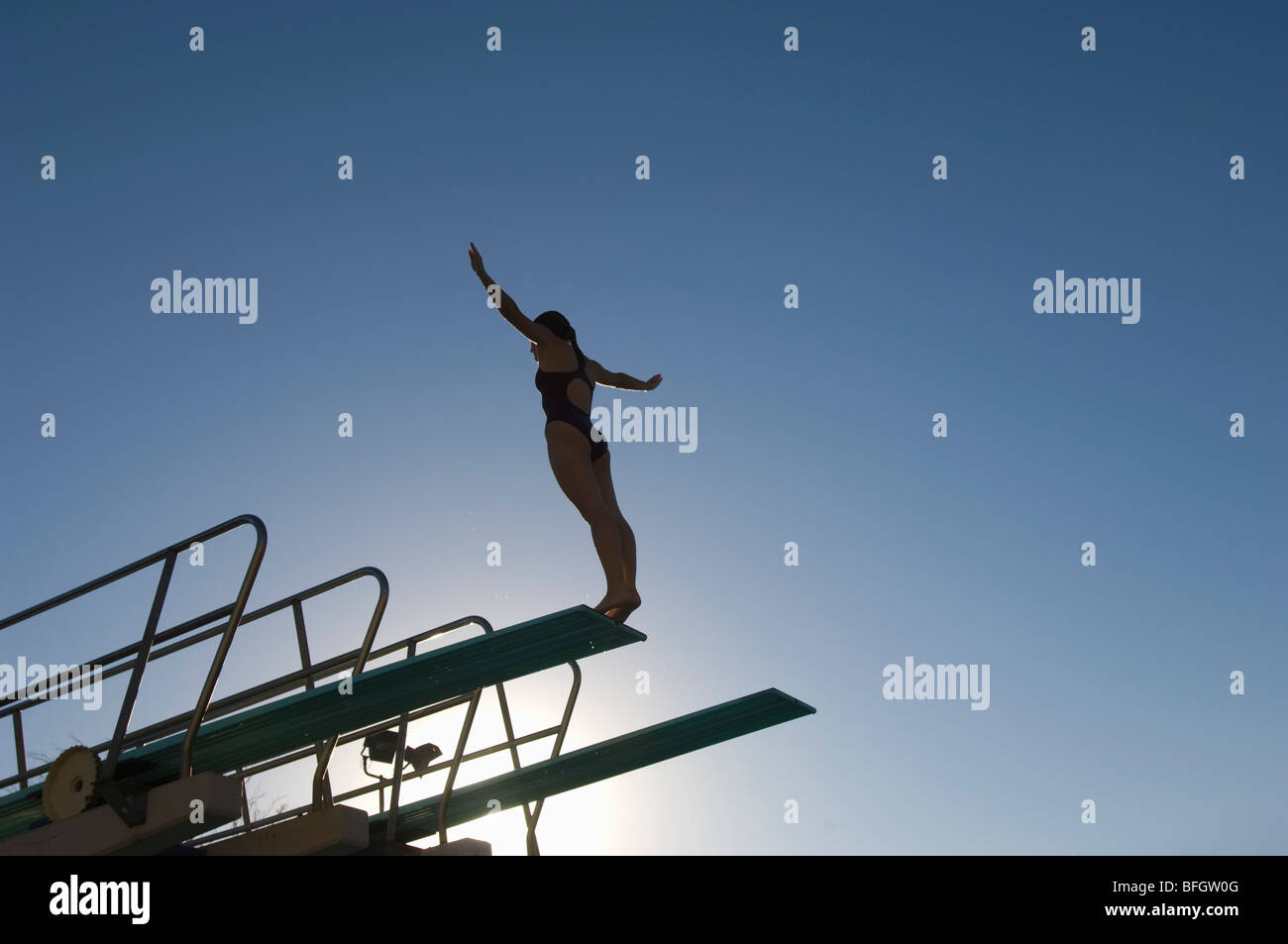 Female swimmer standing on diving board at sunset Stock Photo - Alamy