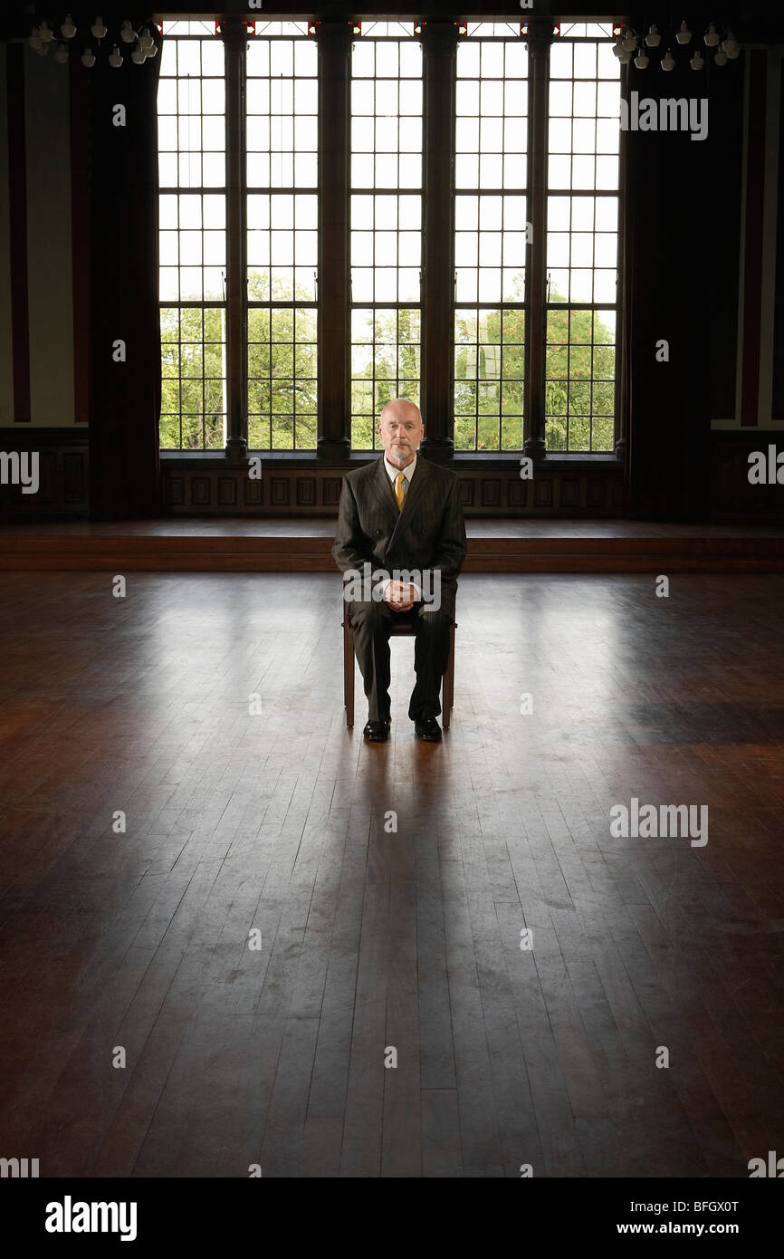 Businessman Sitting in Large, Empty Room Stock Photo - Alamy