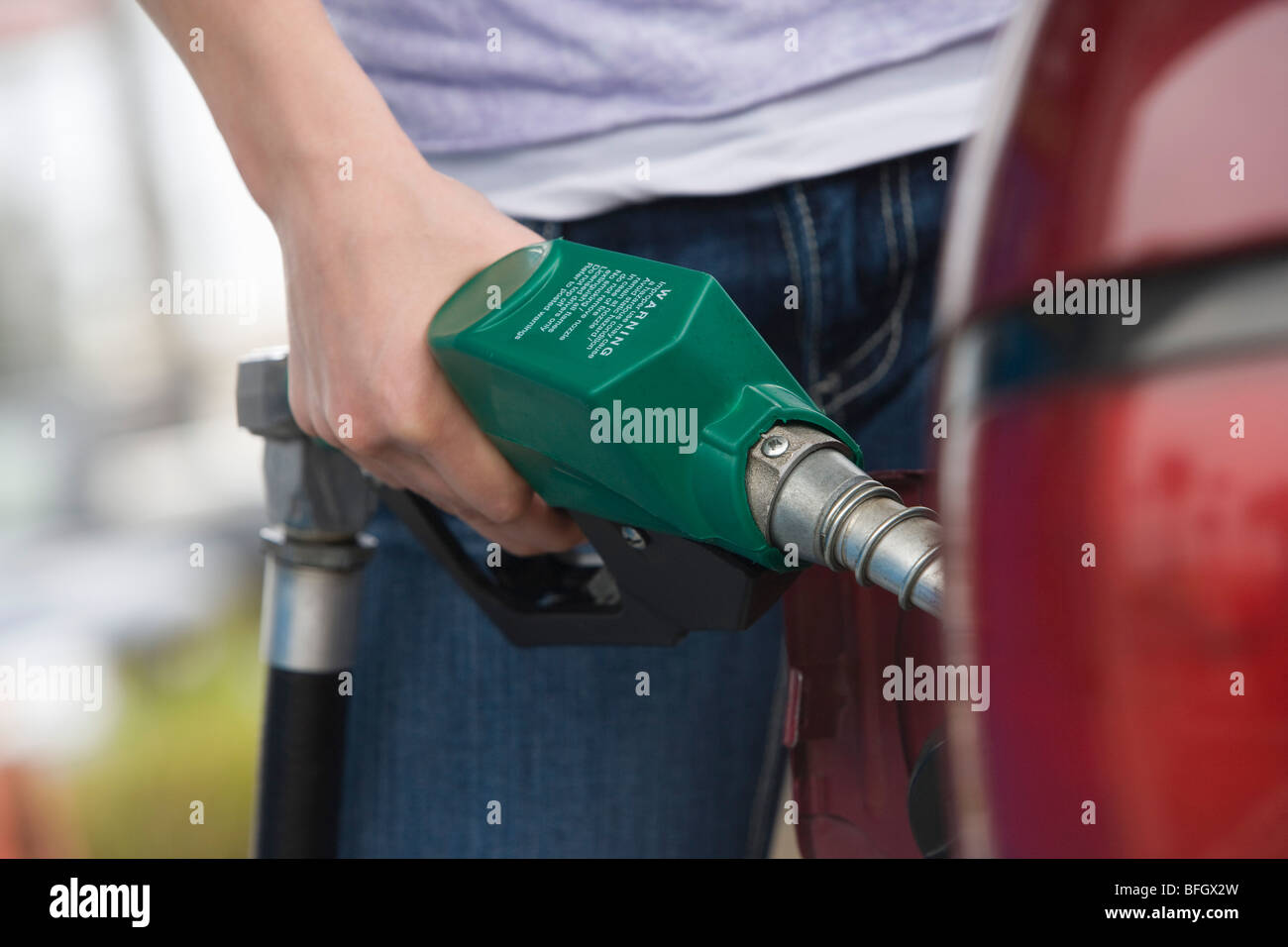 Woman by car with fuel pump, mid section Stock Photo - Alamy