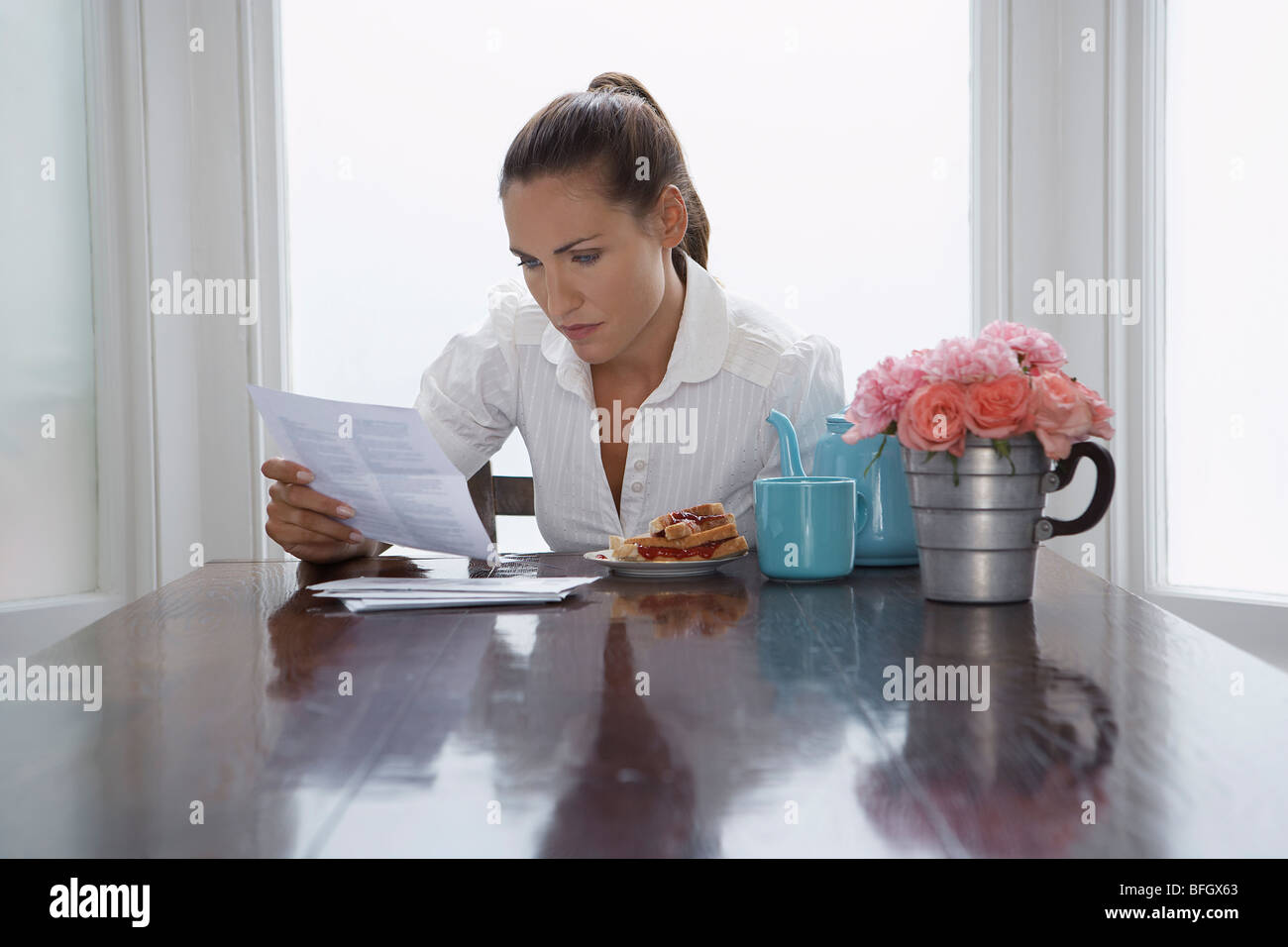 Woman reading at dining room table Stock Photo - Alamy