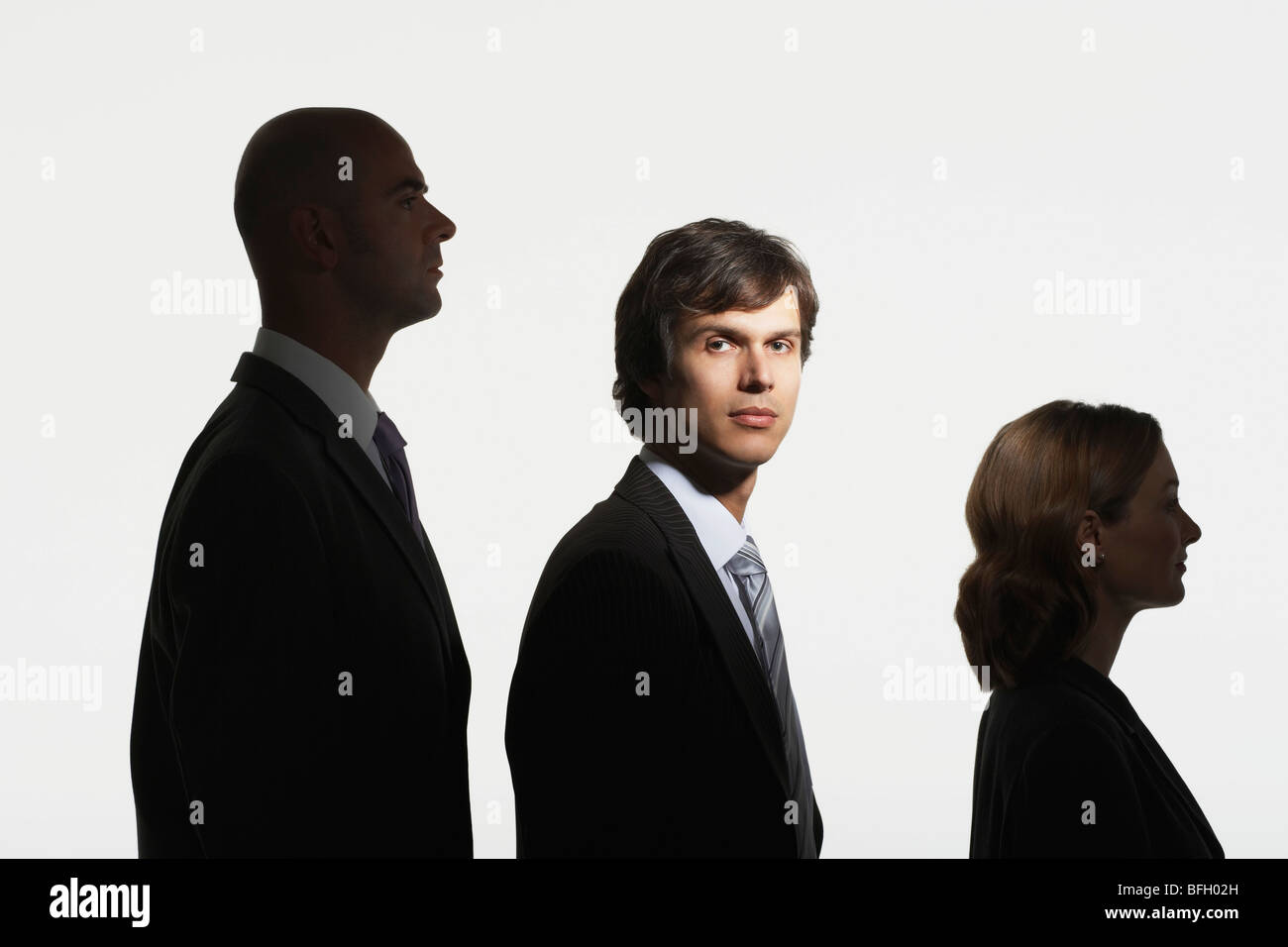 Businesspeople standing in row, in height order, middle man facing ...