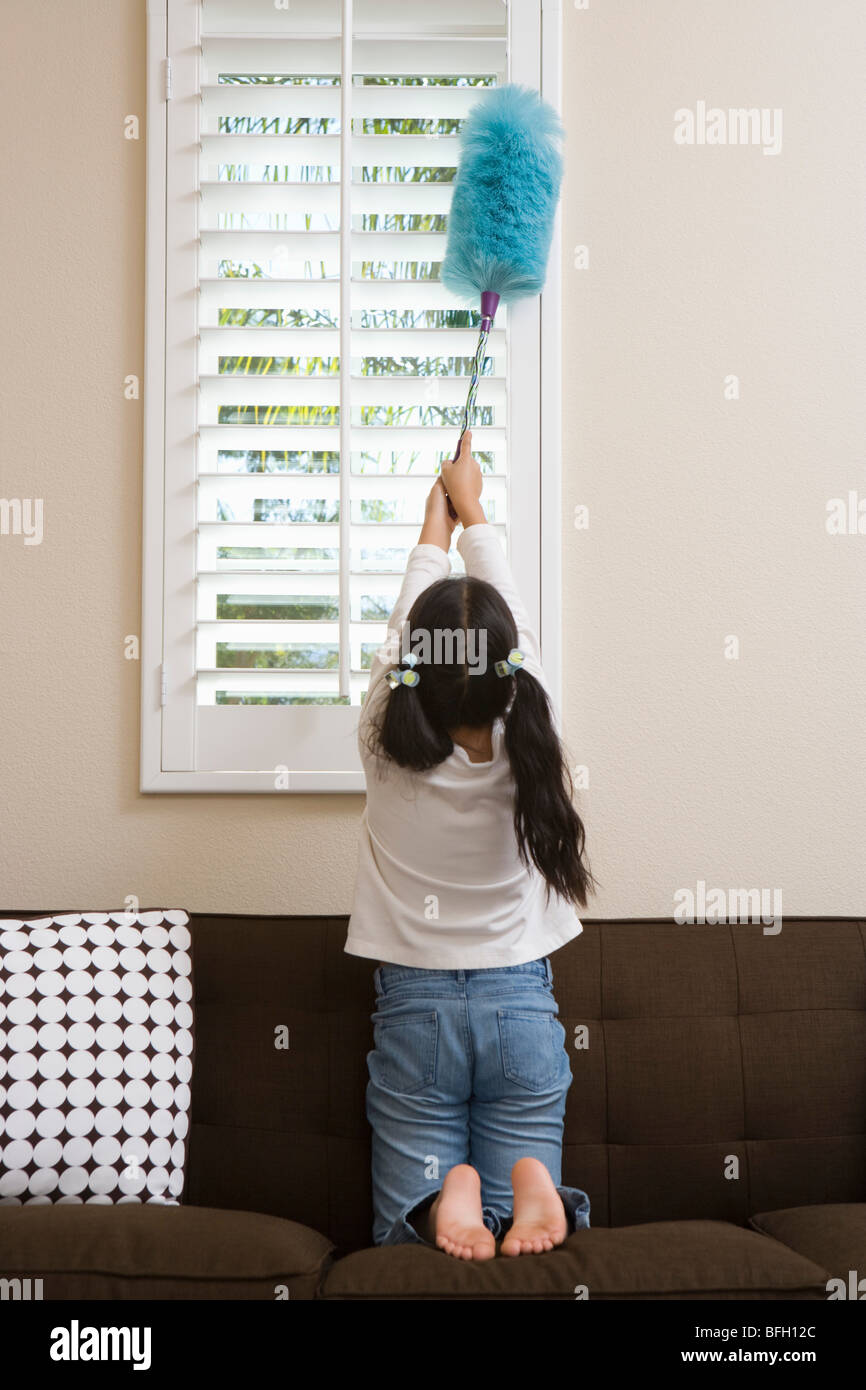 Girl (10-12) dusting window Stock Photo - Alamy