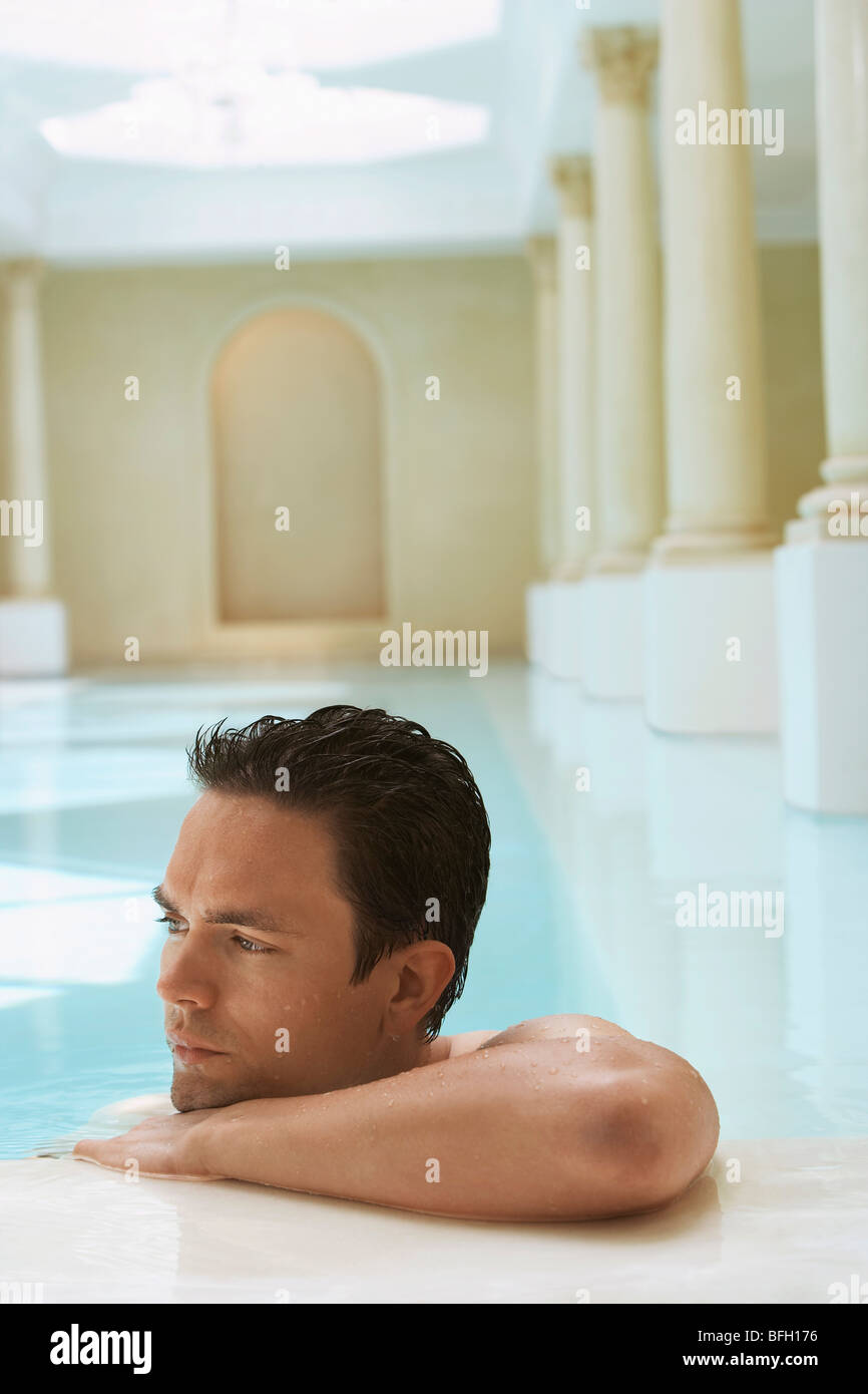 Young man leaning on edge of swimming pool, portrait Stock Photo - Alamy