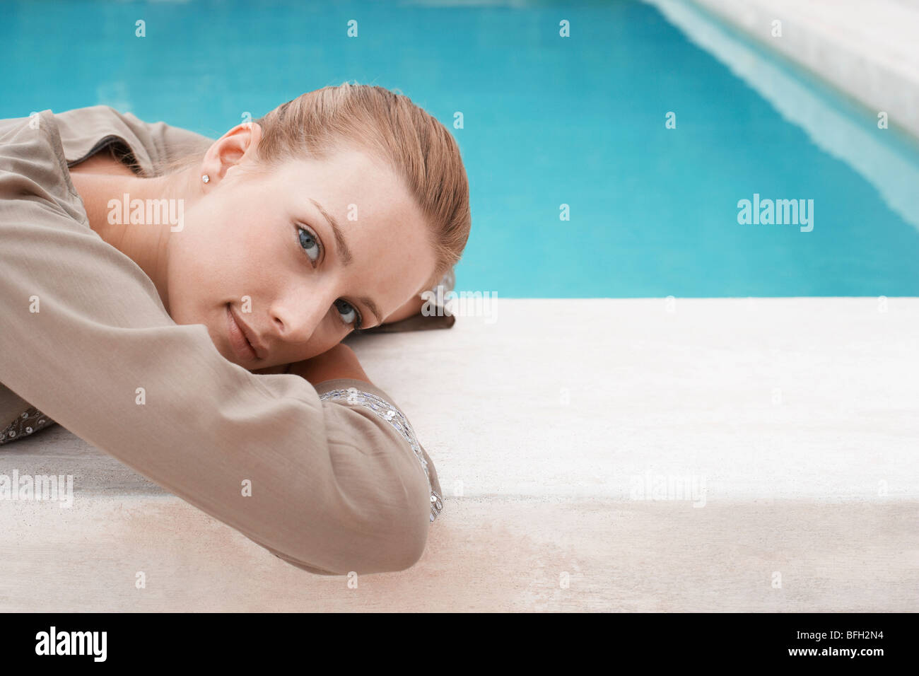 Women lying at edge of swimming pool, portrait Stock Photo - Alamy
