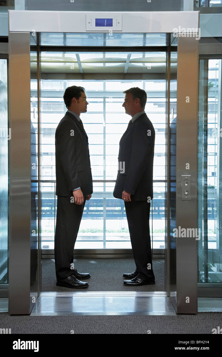 Businessmen standing face to face in elevator Stock Photo - Alamy