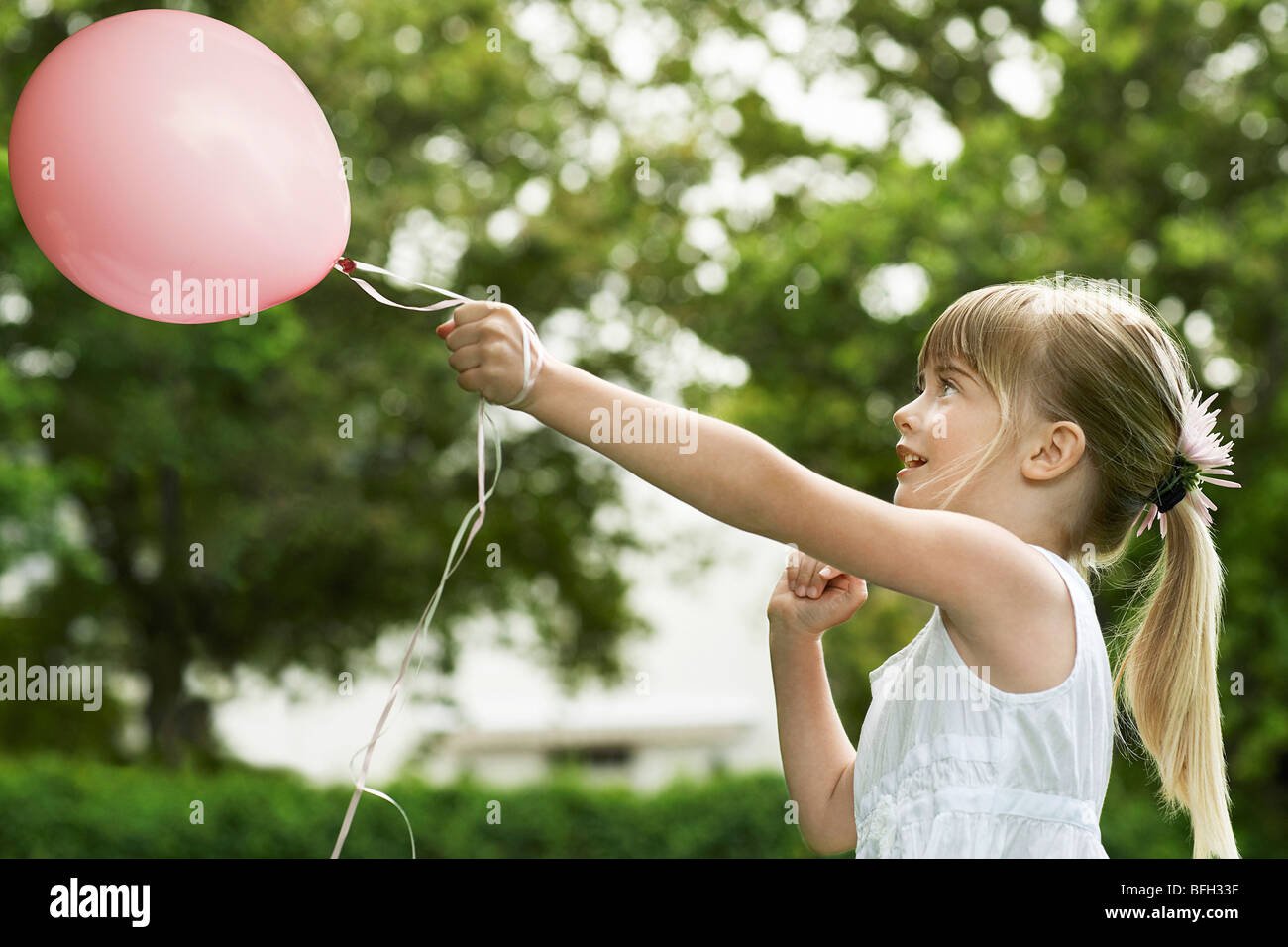 Young girl playing with pink balloon, side view Stock Photo - Alamy