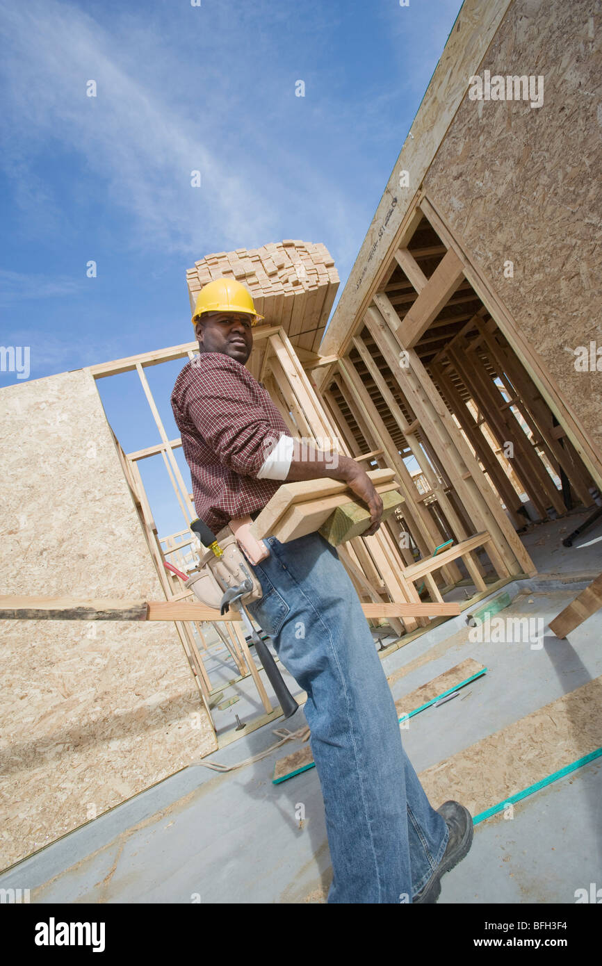 Construction worker carrying wooden plank Stock Photo - Alamy