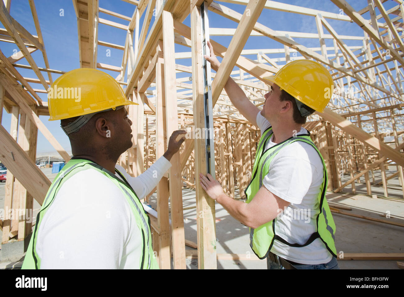 Two construction workers measuring building framework Stock Photo - Alamy