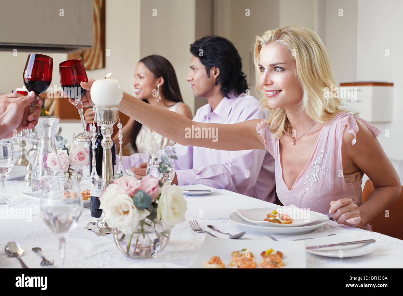 Young woman in dress toasting at formal dinner party Stock Photo - Alamy