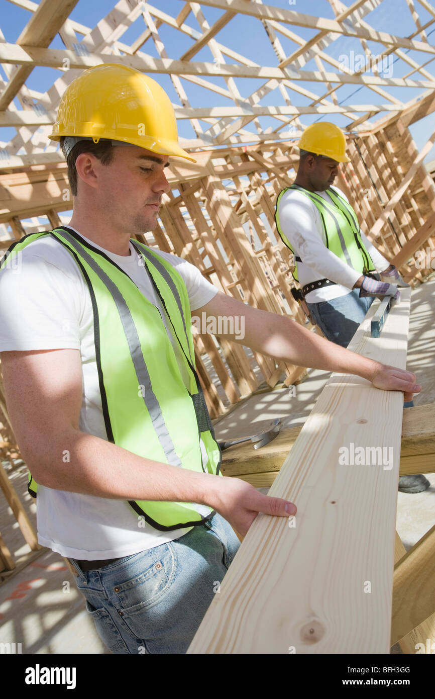 Two construction workers measuring wooden plank Stock Photo - Alamy