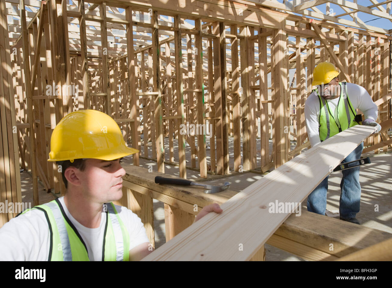 Two construction workers measuring wooden plank Stock Photo - Alamy