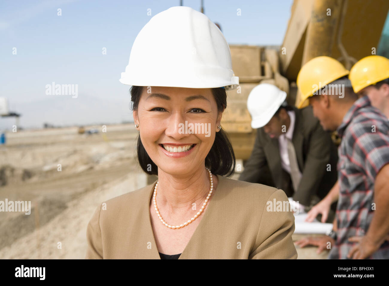 Female surveyor and construction workers on site, portrait Stock Photo ...
