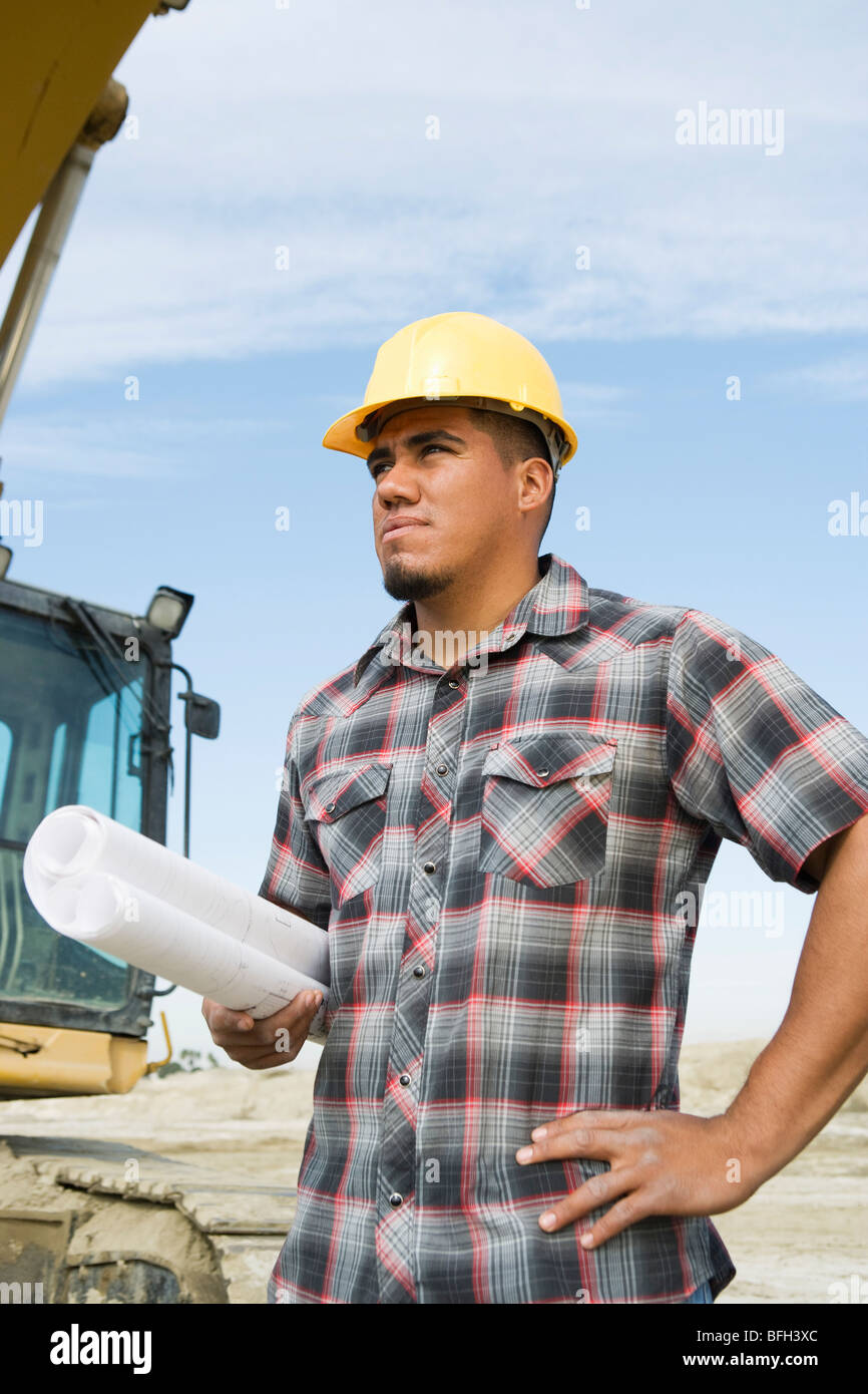 Construction worker holding blueprints on site Stock Photo - Alamy