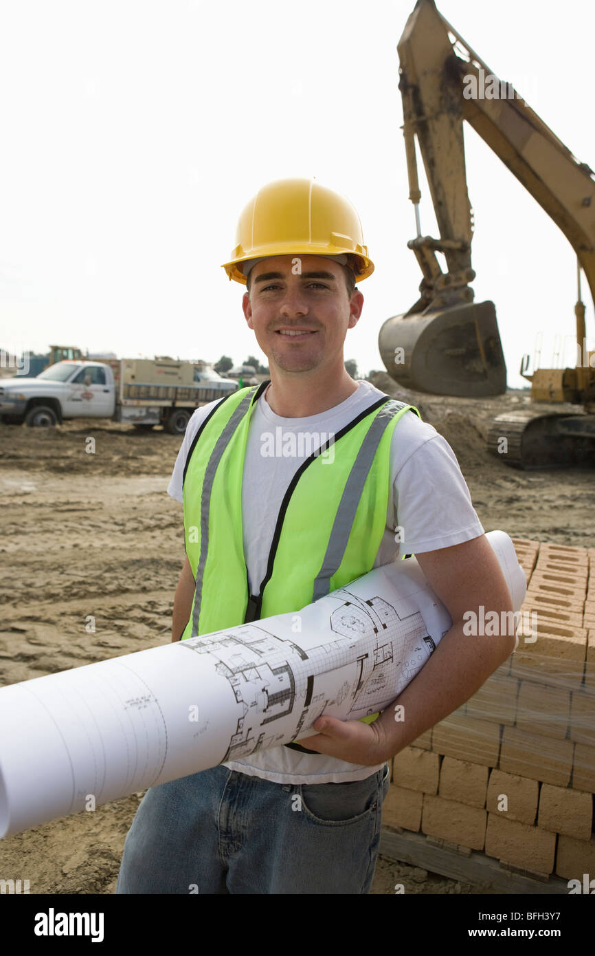 Construction worker holding blueprints on site, portrait Stock Photo ...