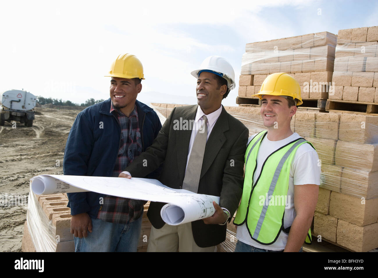 Three construction workers standing on construction site with ...