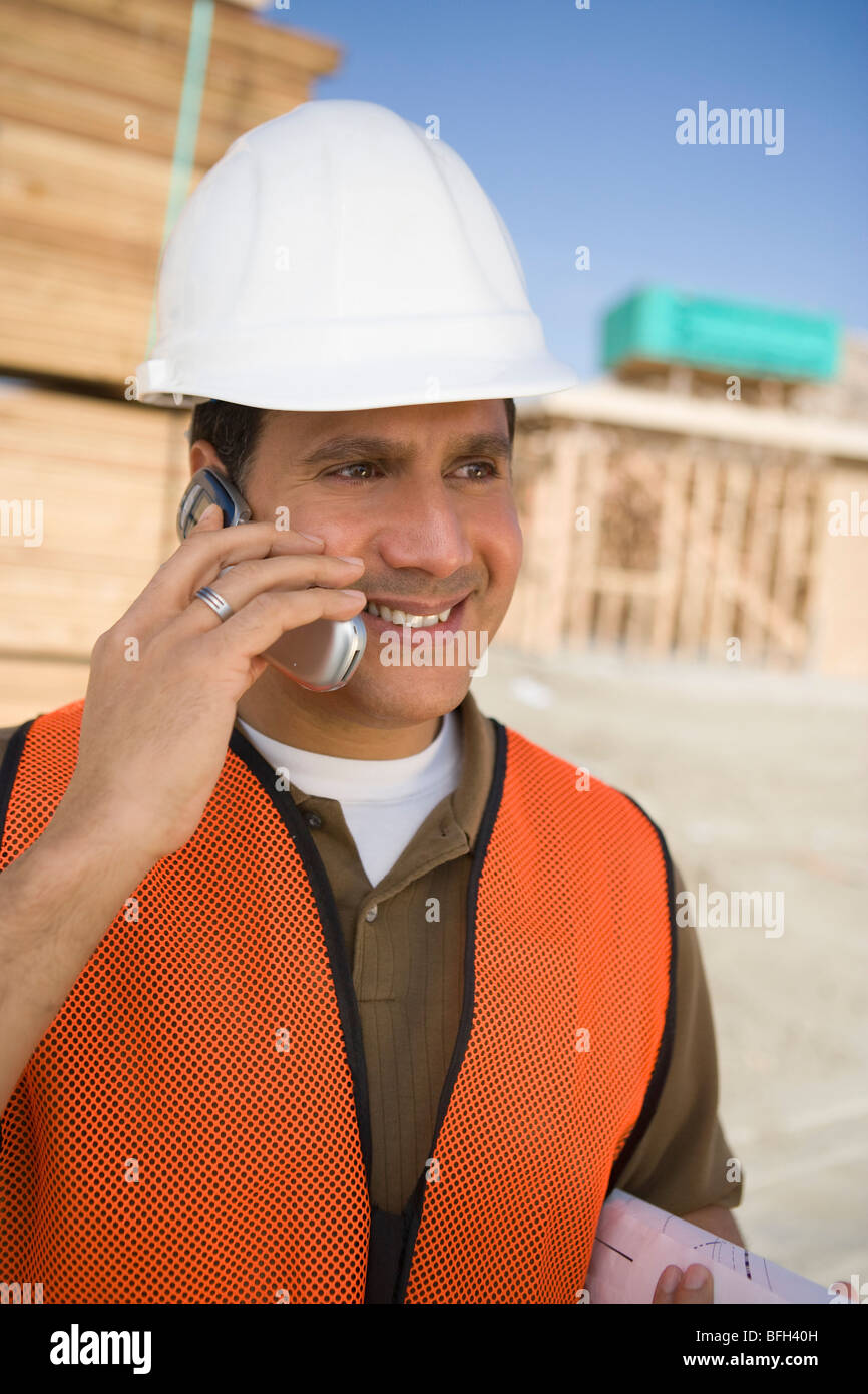 Construction worker standing on construction site and talking in mobile ...