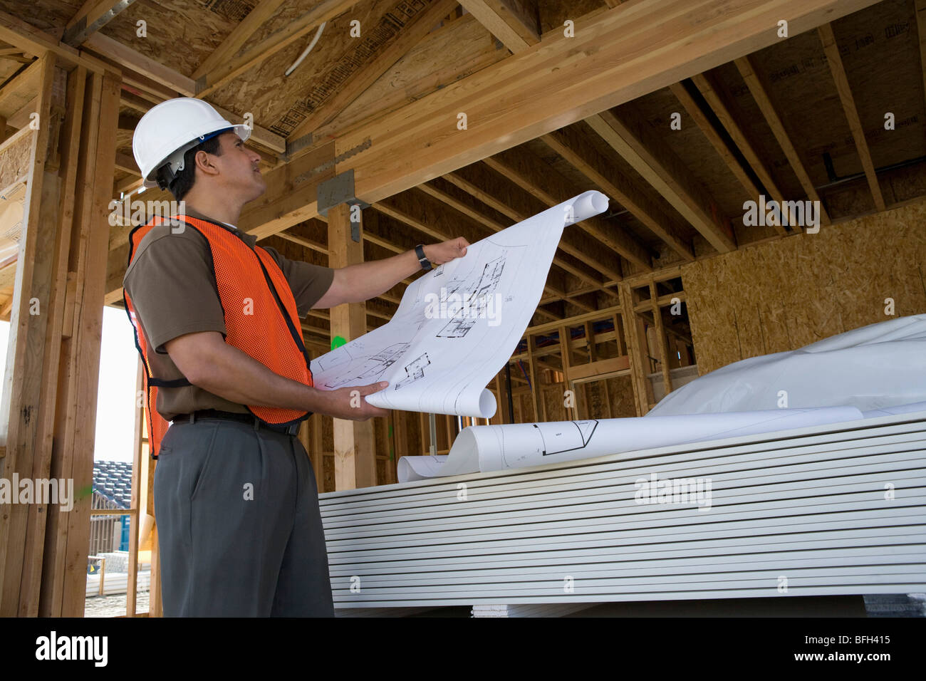 Construction worker observing half constructed house while holding ...