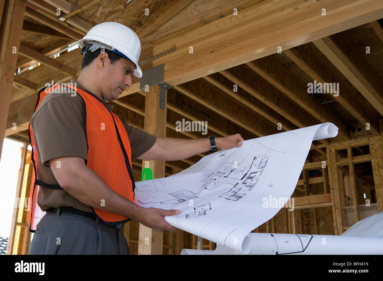 Construction worker observing half constructed house while holding ...