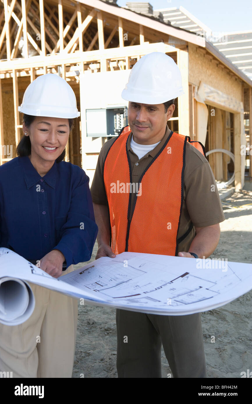 Architect and construction worker looking at blueprints on construction ...
