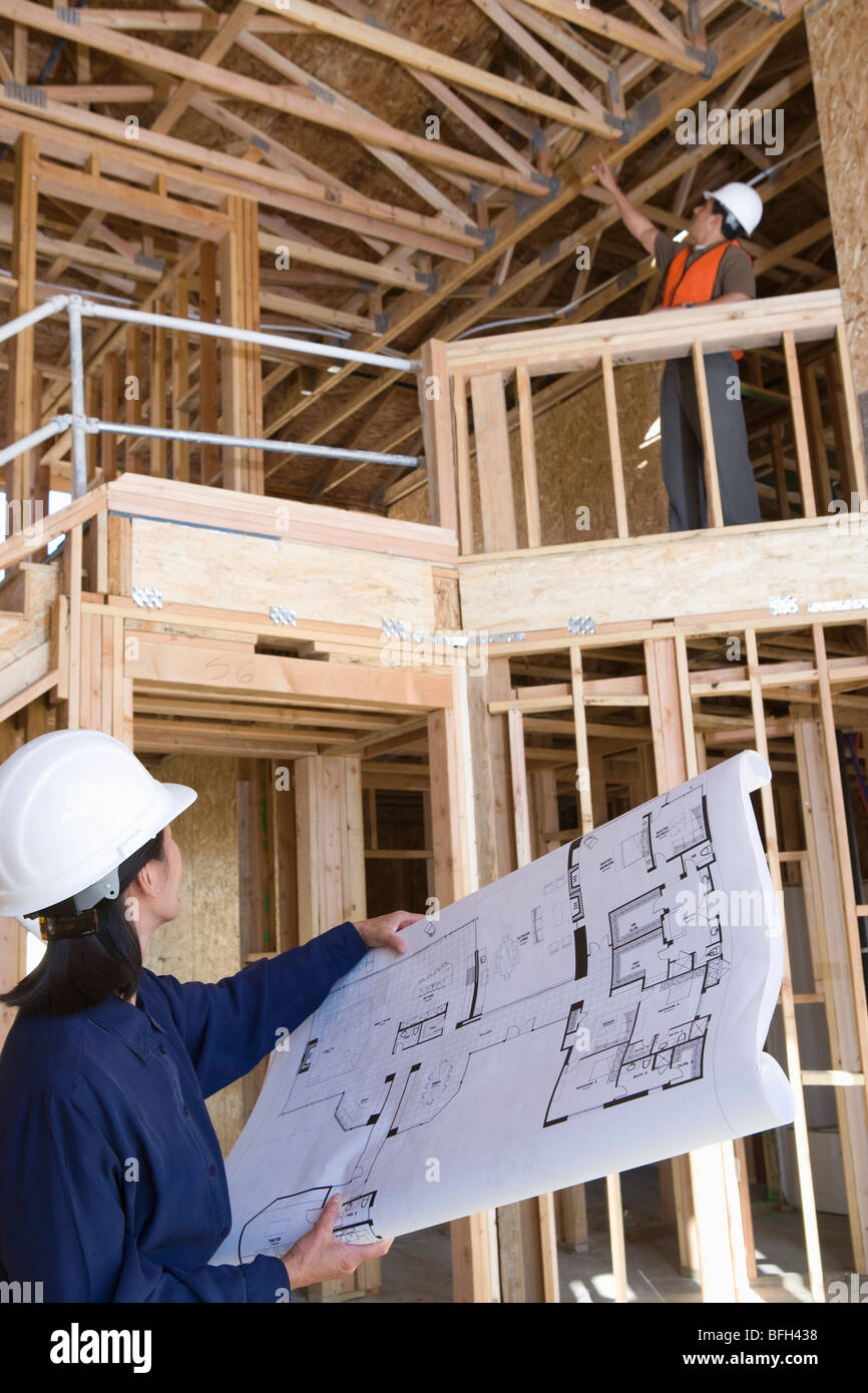 Architect and construction worker examining half constructed house ...