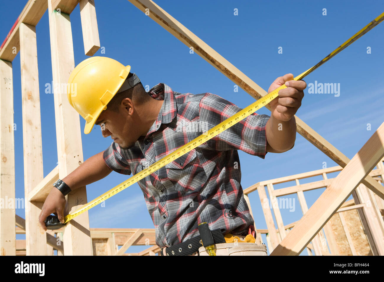 Construction worker measuring half constructed wall with tape measure ...
