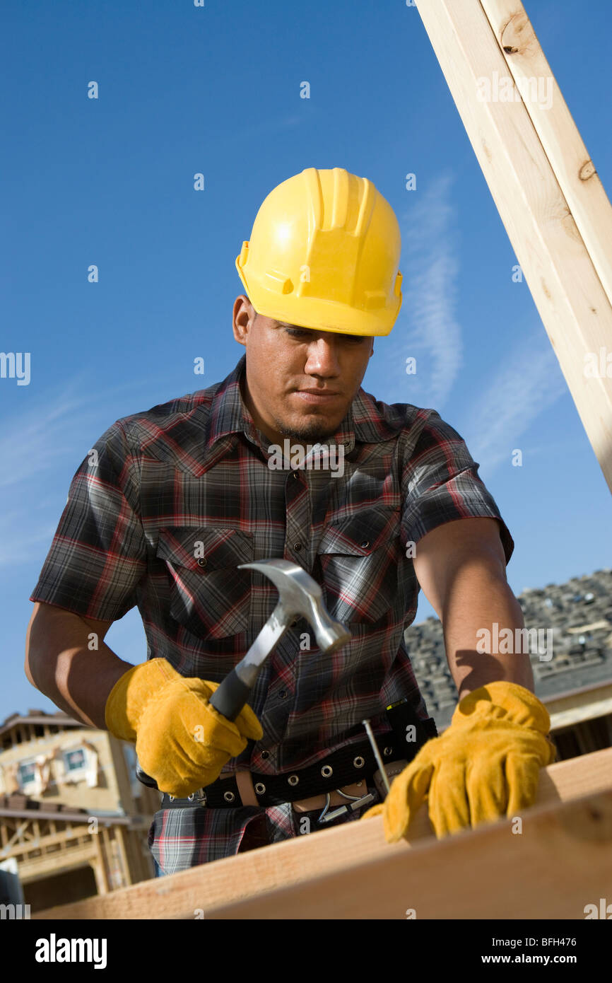 Construction worker hammering nail on construction site Stock Photo - Alamy