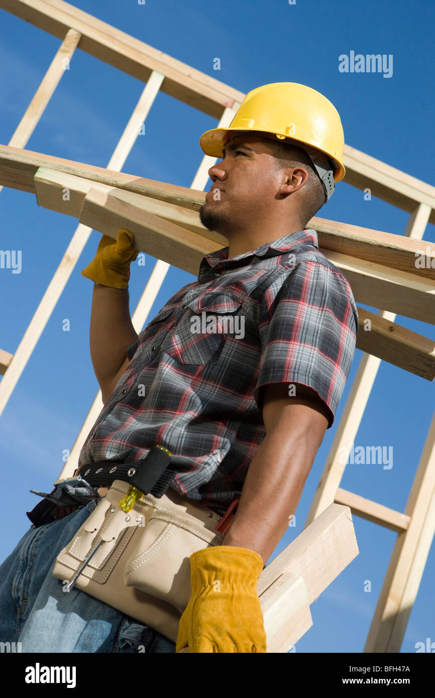 Construction worker carrying planks on construction site Stock Photo ...