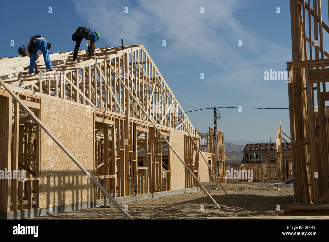 Two construction workers working on roof of half constructed house ...