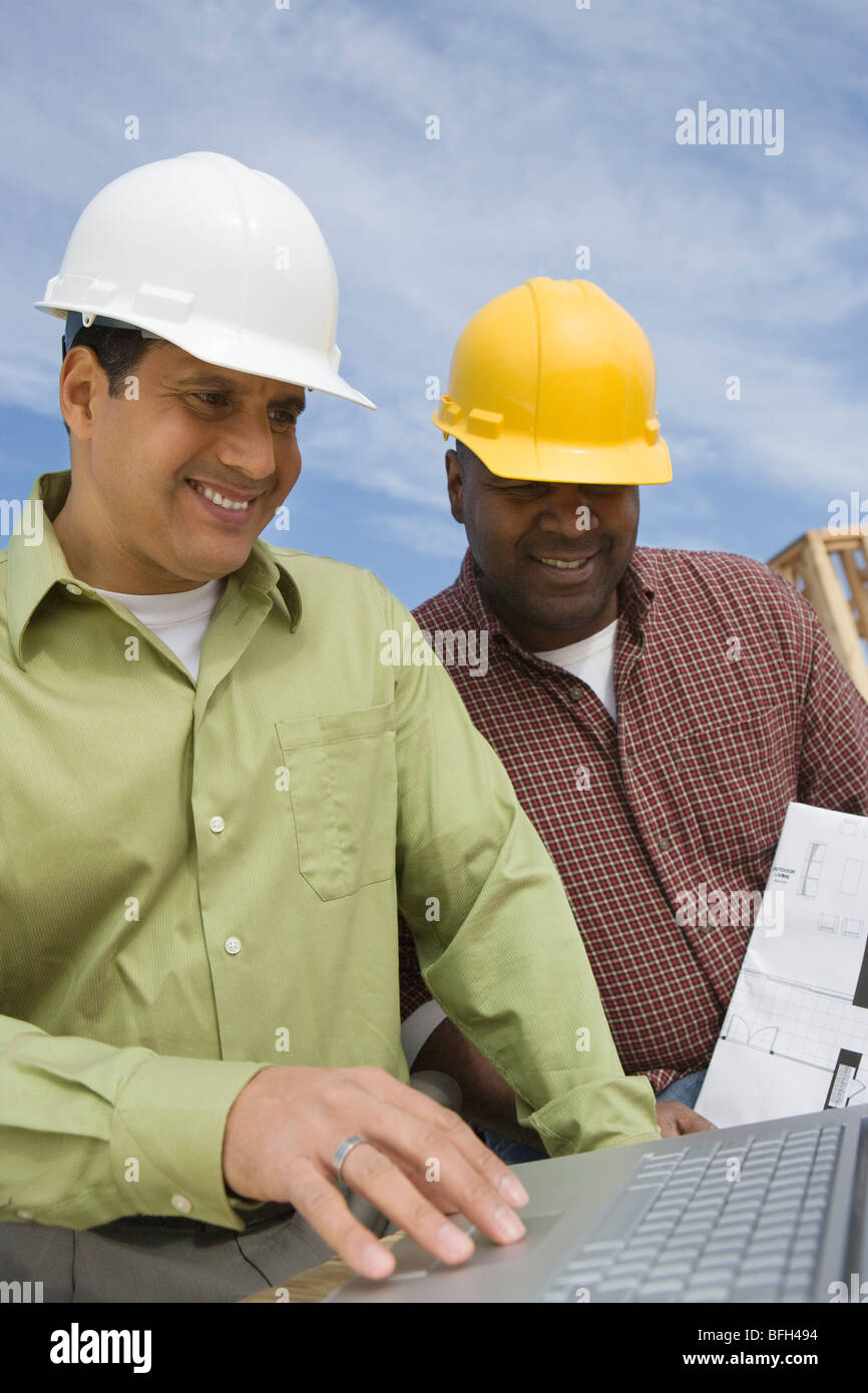 Architect and construction worker using laptop on construction site ...