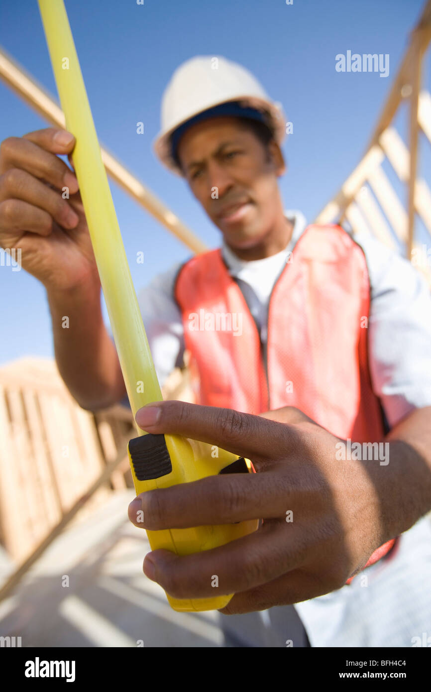 Construction worker measuring with tape measure Stock Photo - Alamy