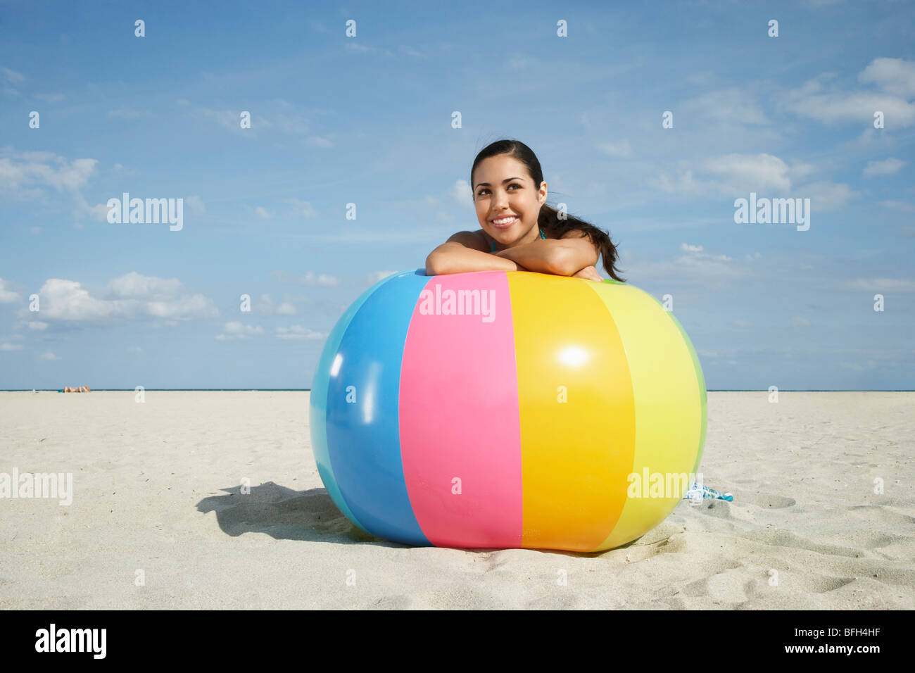 Teenage girl (16-17) sitting behind beach ball on beach, portrait Stock ...