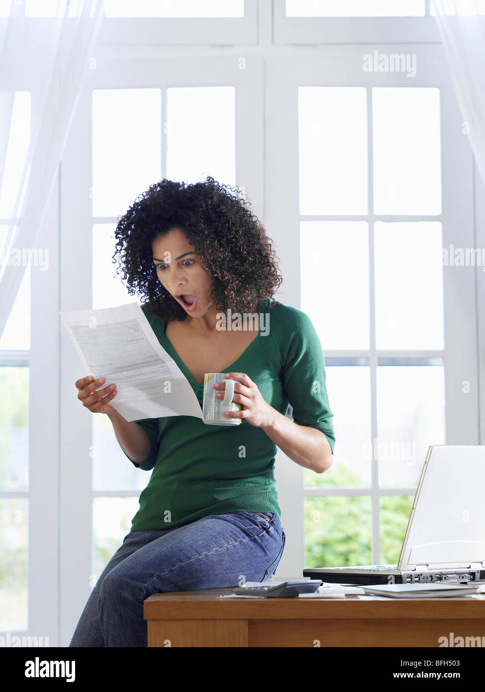 Woman reading paper document, sitting on desk Stock Photo - Alamy