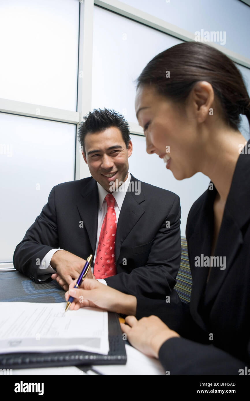 Businesswoman singing agreement with businessman Stock Photo - Alamy