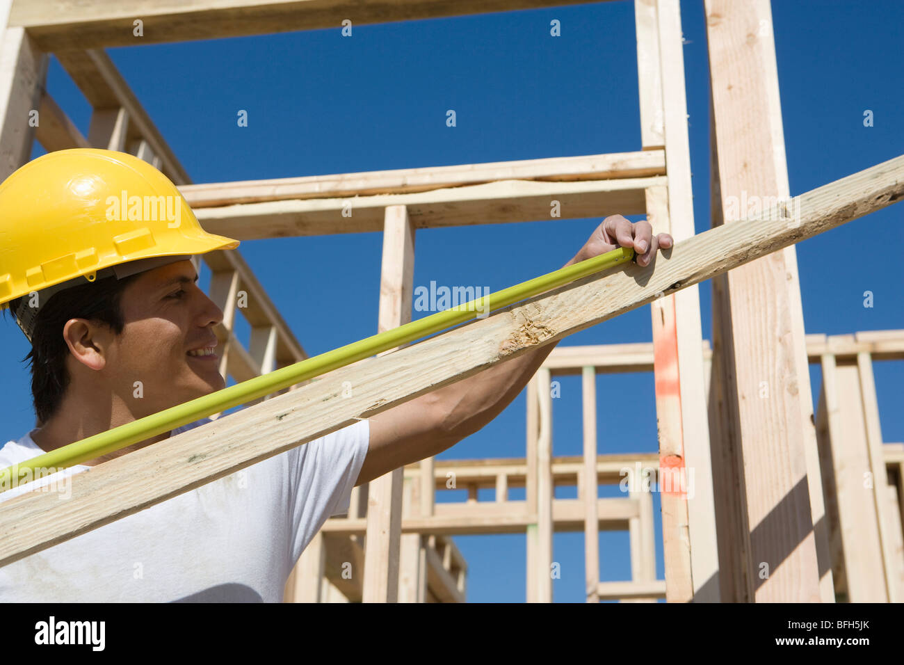 Construction worker measuring plank Stock Photo - Alamy